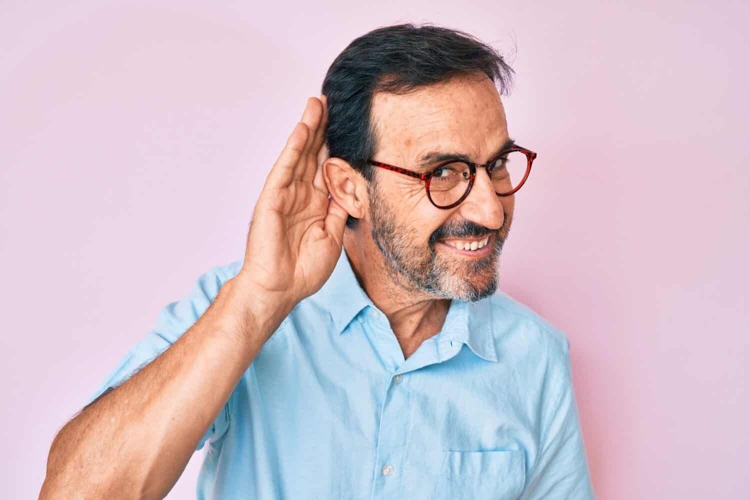 Man smiling and holding is ear asif he has one-sided hearing loss. He ...